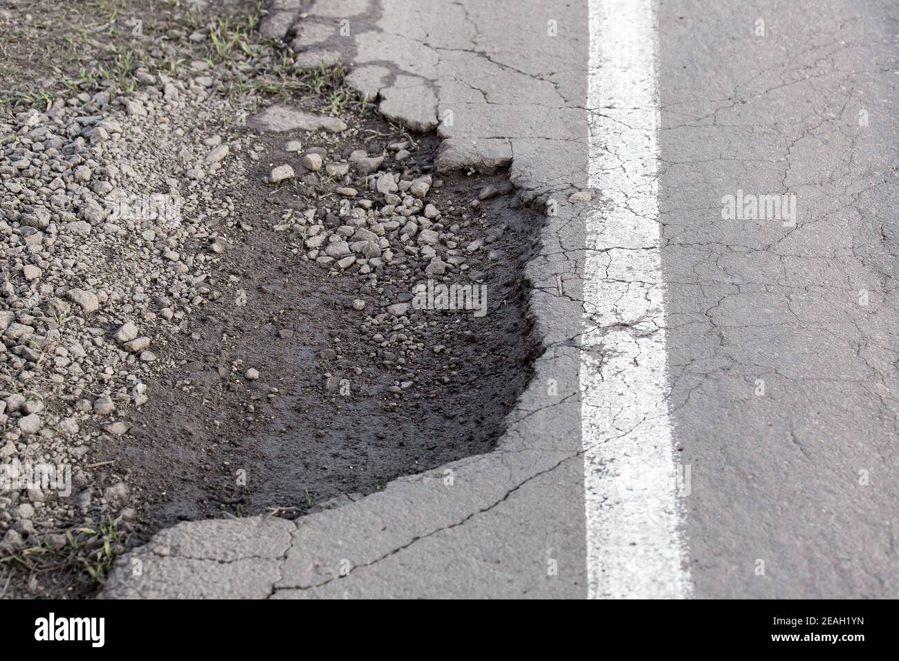 pothole with spoiled asphalt pavement with white markings close up, pit ...