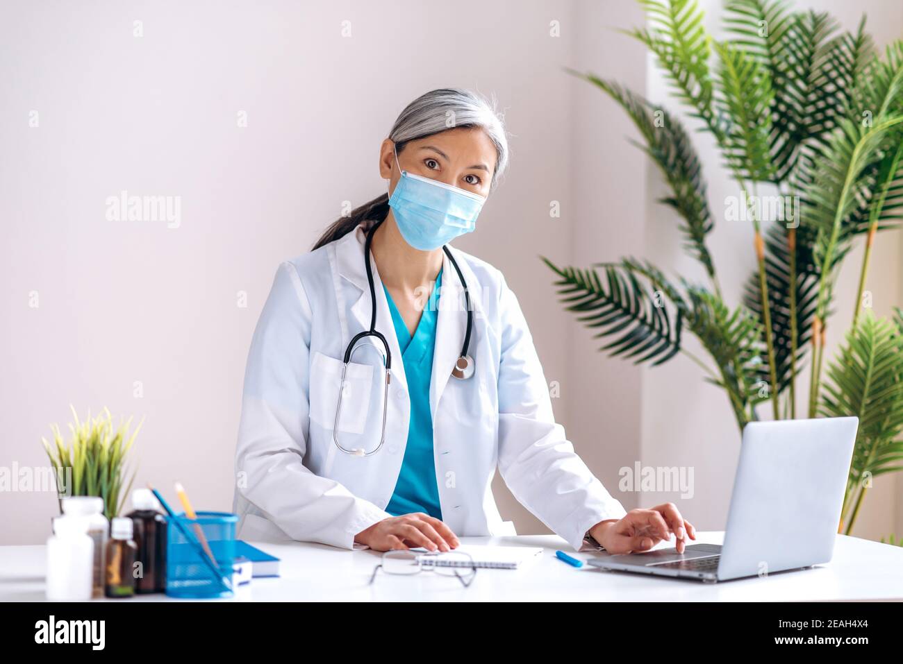 Portrait of female middle aged general doctor with gray hair dressed in ...
