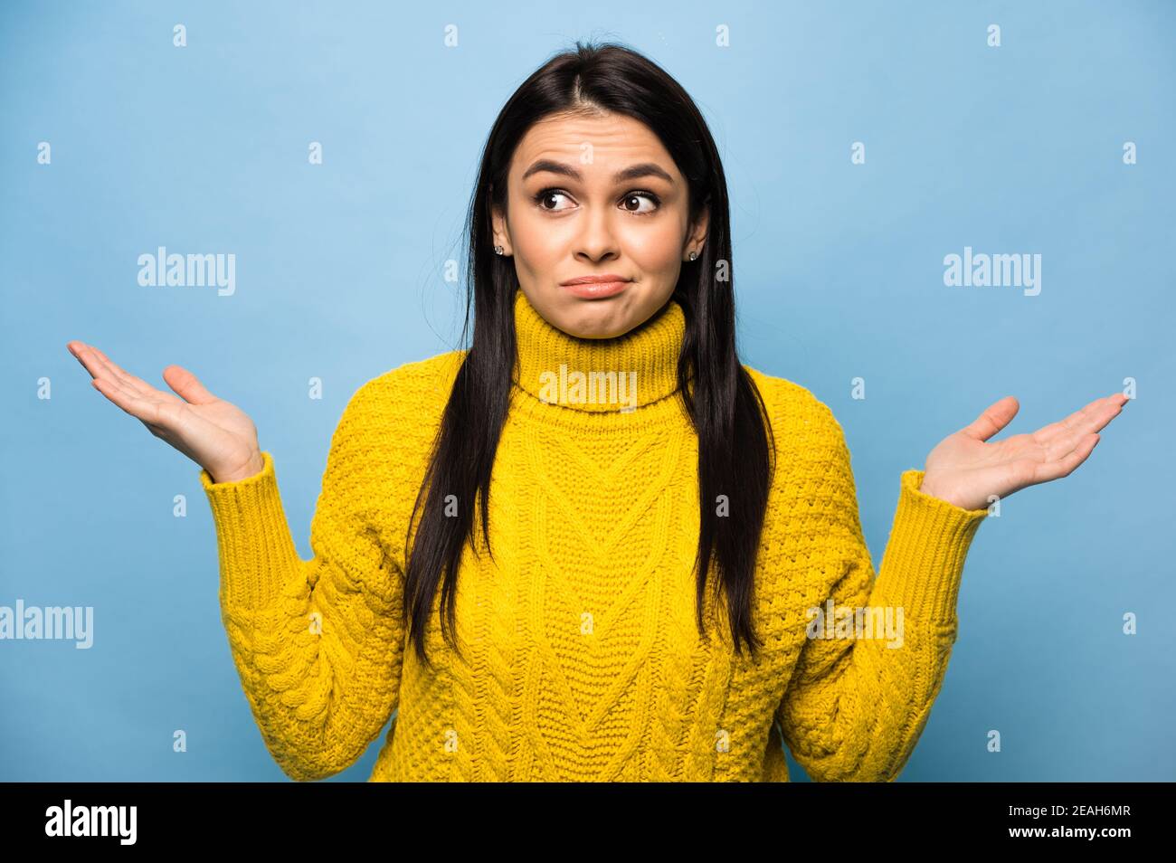 Confused caucasian pretty girl dressed in yellow sweater standing on ...