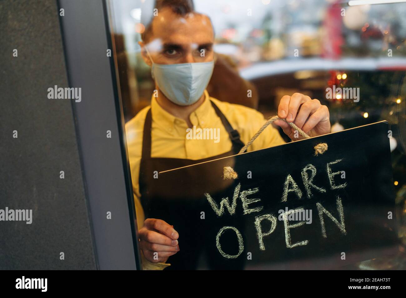 Welcome. Satisfied caucasian male waiter or barista showing signboard ...