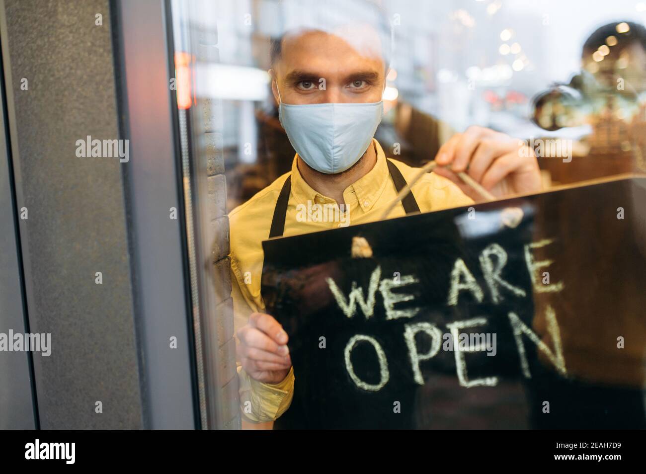 Welcome. Satisfied caucasian male waiter or barista showing signboard ...