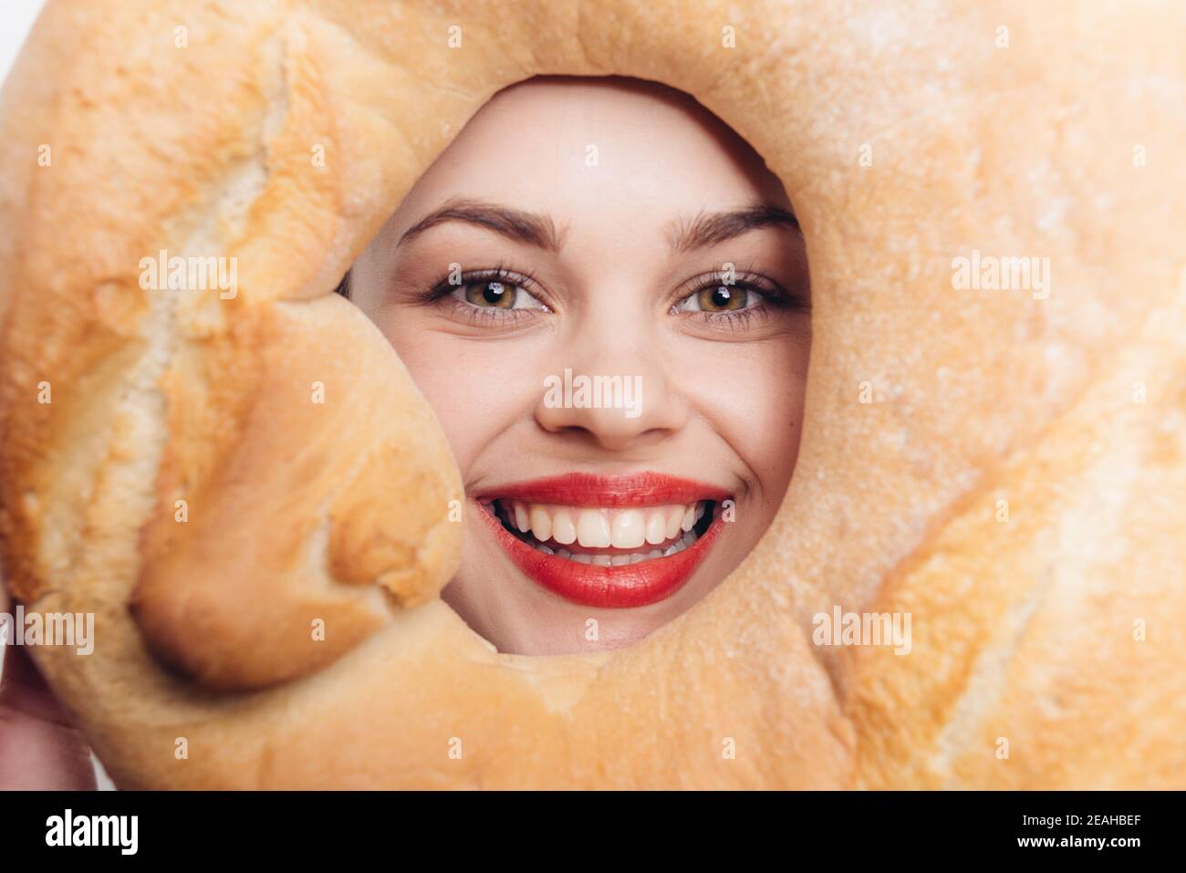 happy woman with round loaf of bread in front of face bright makeup ...