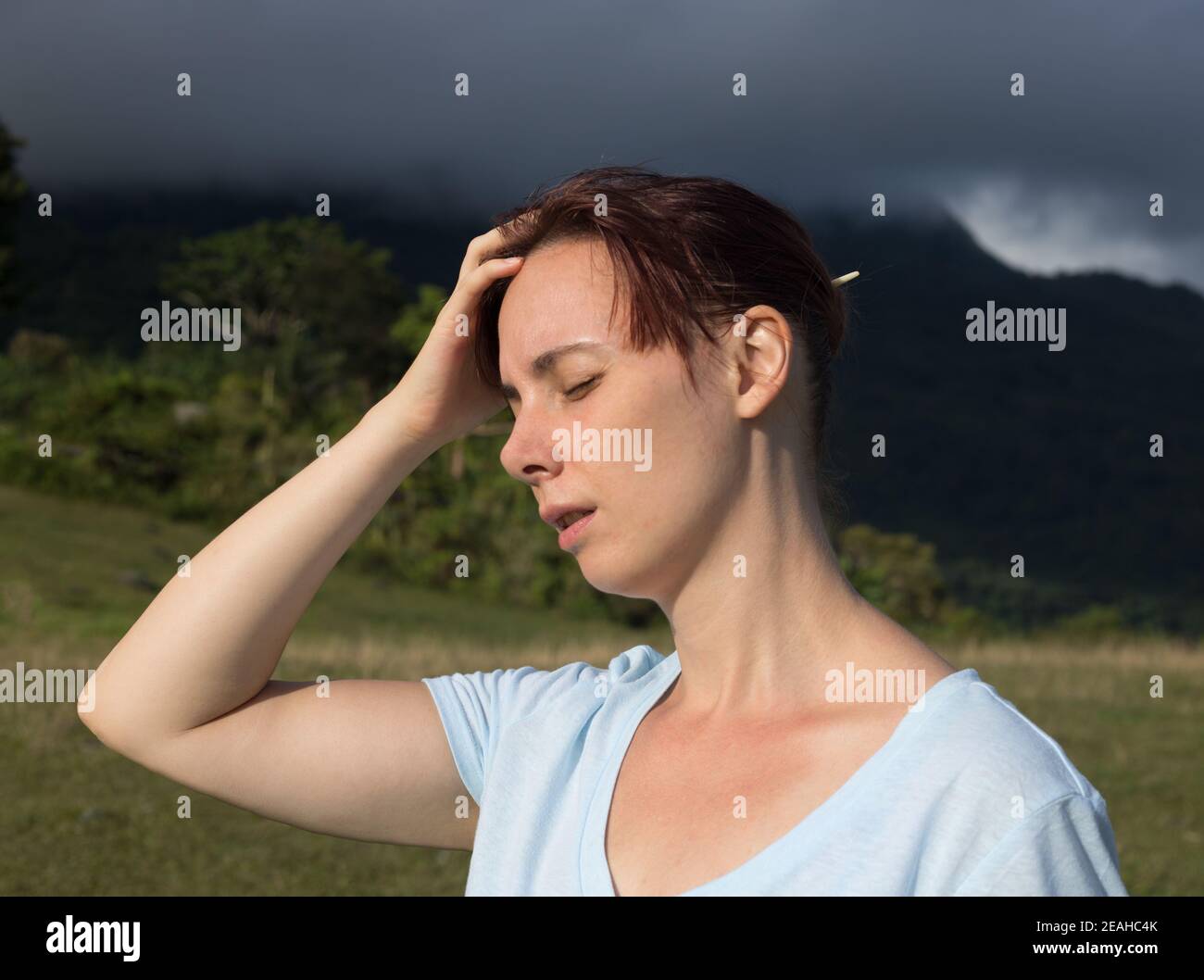 Woman with headache on sky storm background. A woman with a headache on ...