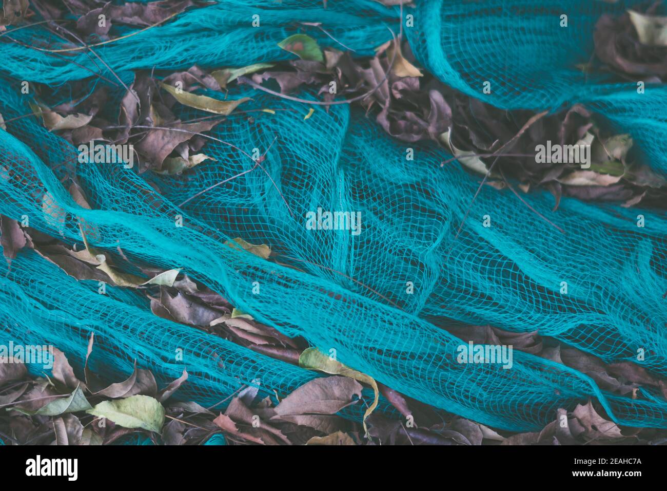 Close-up view of green nylon multi colorful bright fish nets in a pile ...