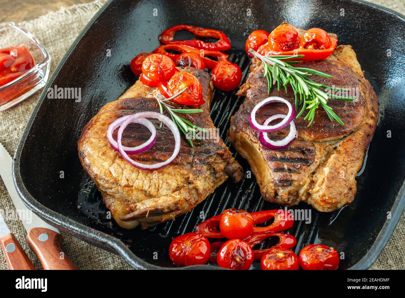Fresh juicy roasted red meat on grill pen, with spices and vegetables ...