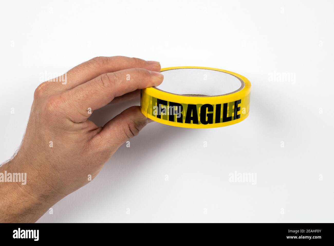 Fragile, yellow warning tape in a man's hands on a white background ...