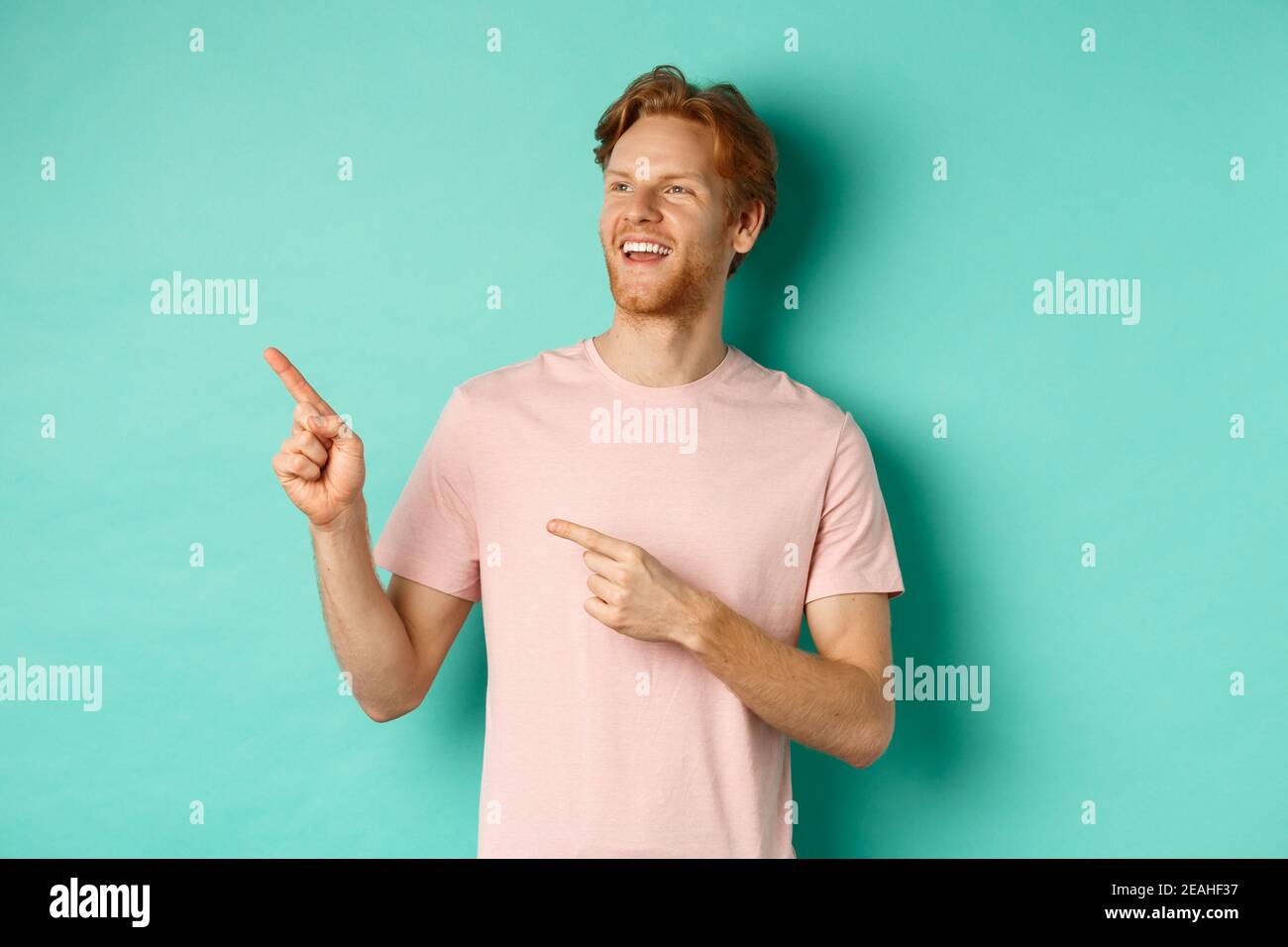 Dreamy handsome guy with red hair, smiling and looking at upper left ...
