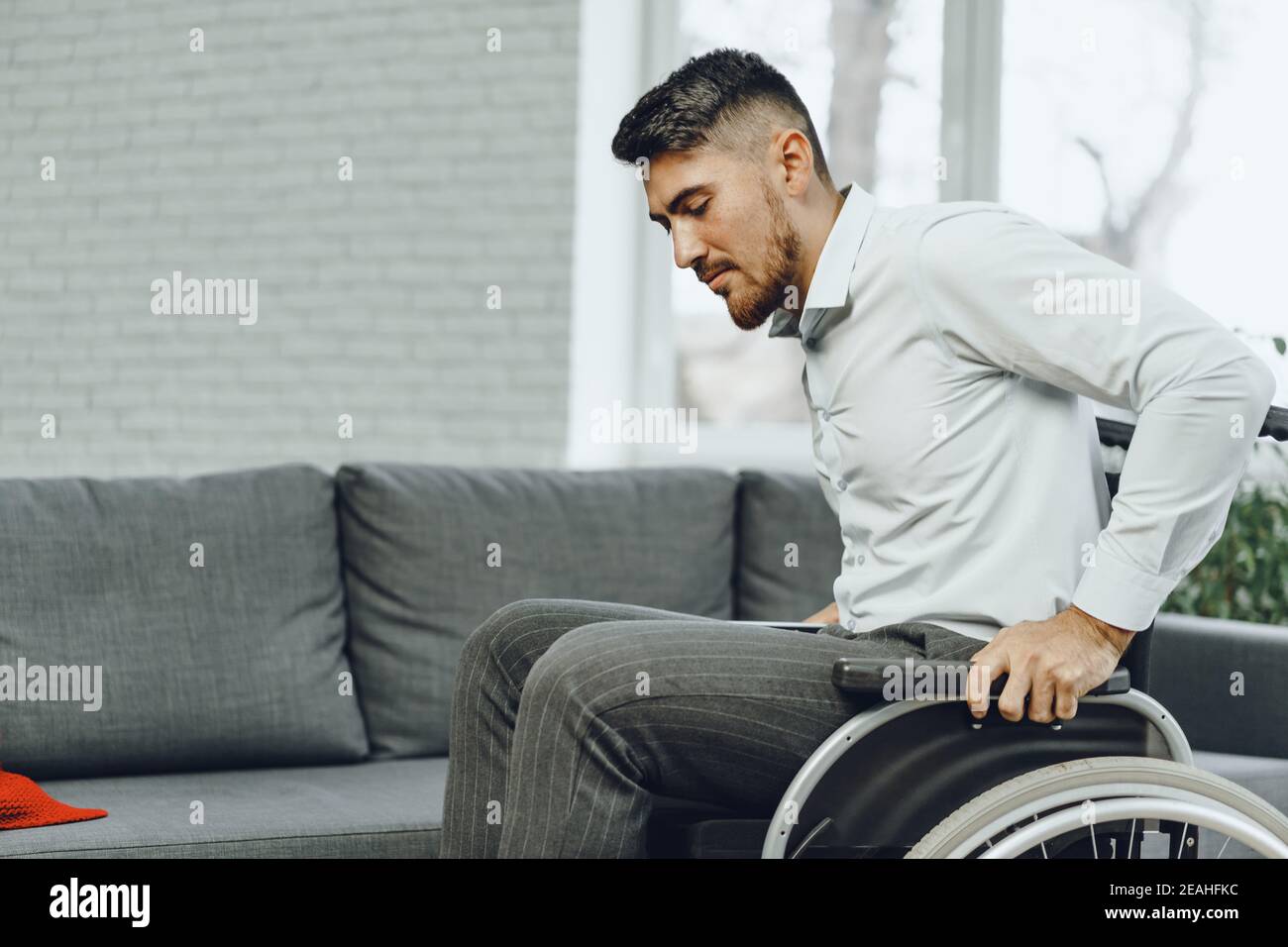 Disabled man tries to sit down on a sofa from wheelchair Stock Photo ...
