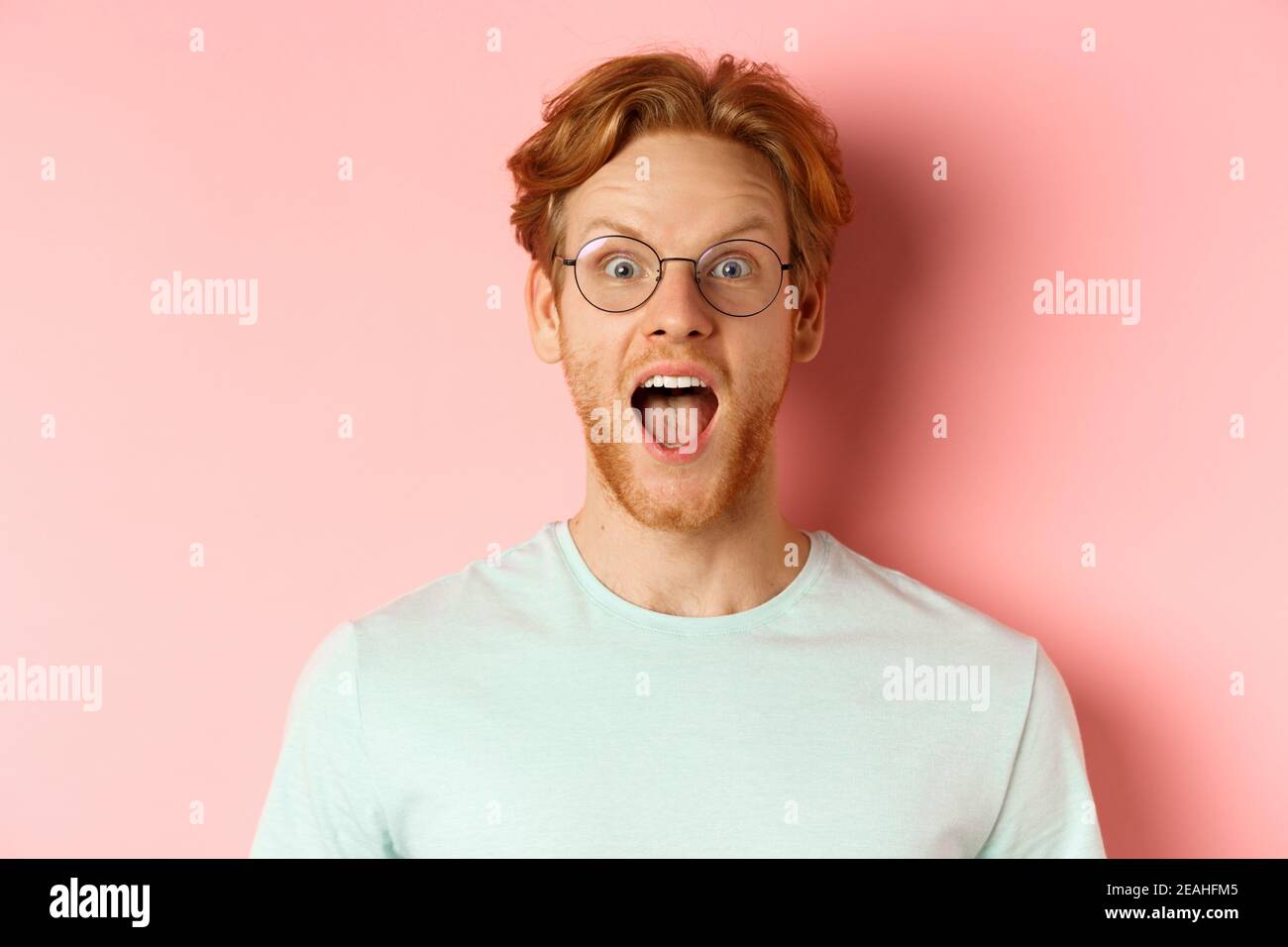 Close up of surprised redhead man raising eyebrows and scream with joy ...