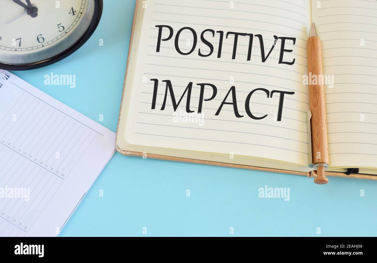 Positive Impact text written in notebook, light blue background ...