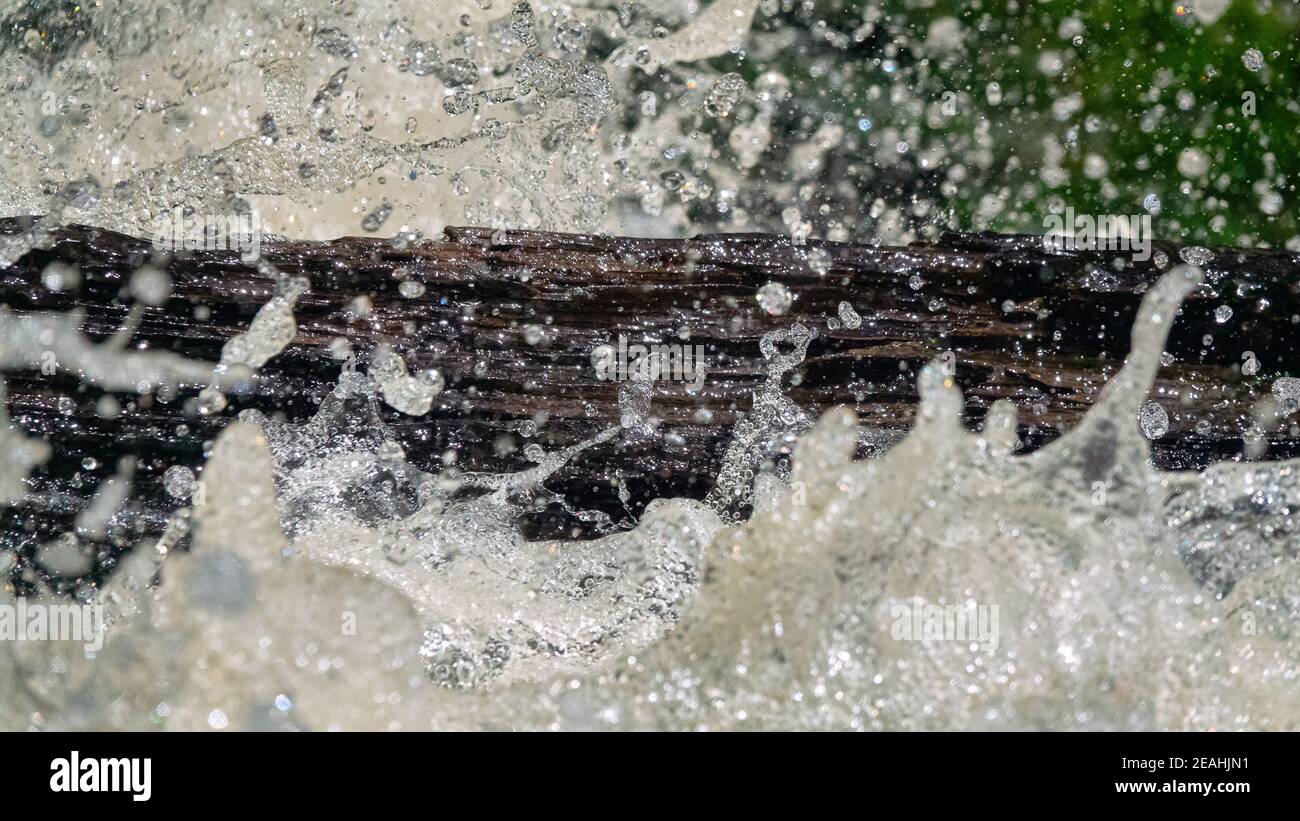 Water backgrounds with foam spray fast flow.The log is stuck in ...