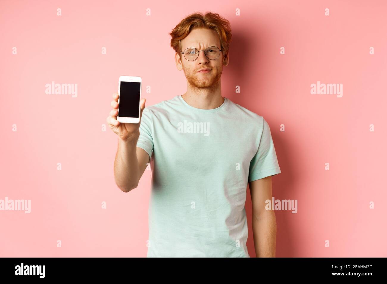 Disappointed male model frowning, showing smartphone screen, standing ...