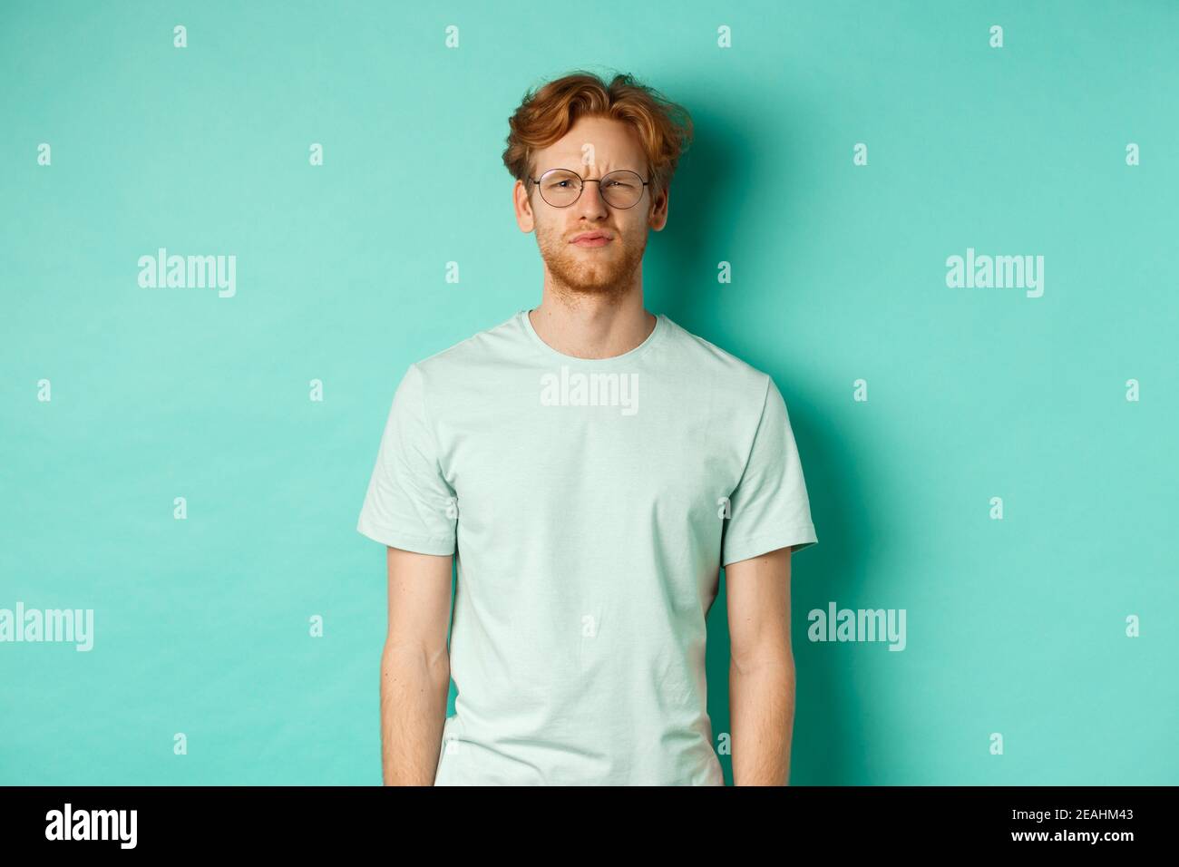 Confused young redhead man in glasses staring at camera puzzled ...