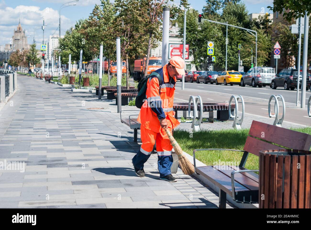 Municipal worker in orange uniform sweep city street, janitor with ...