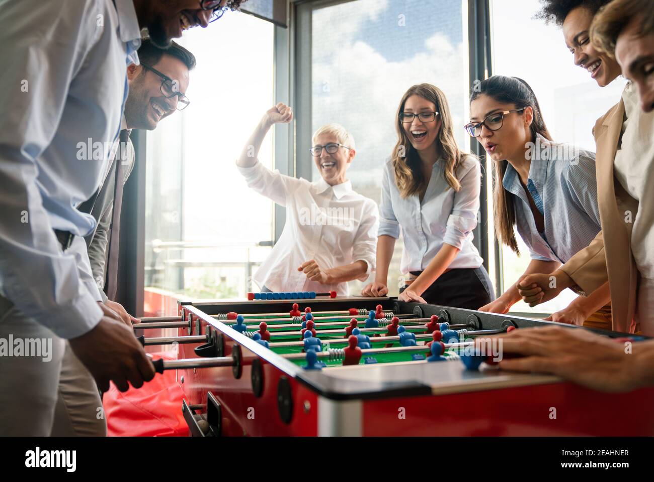 Employees playing table soccer indoor game in the office during break ...