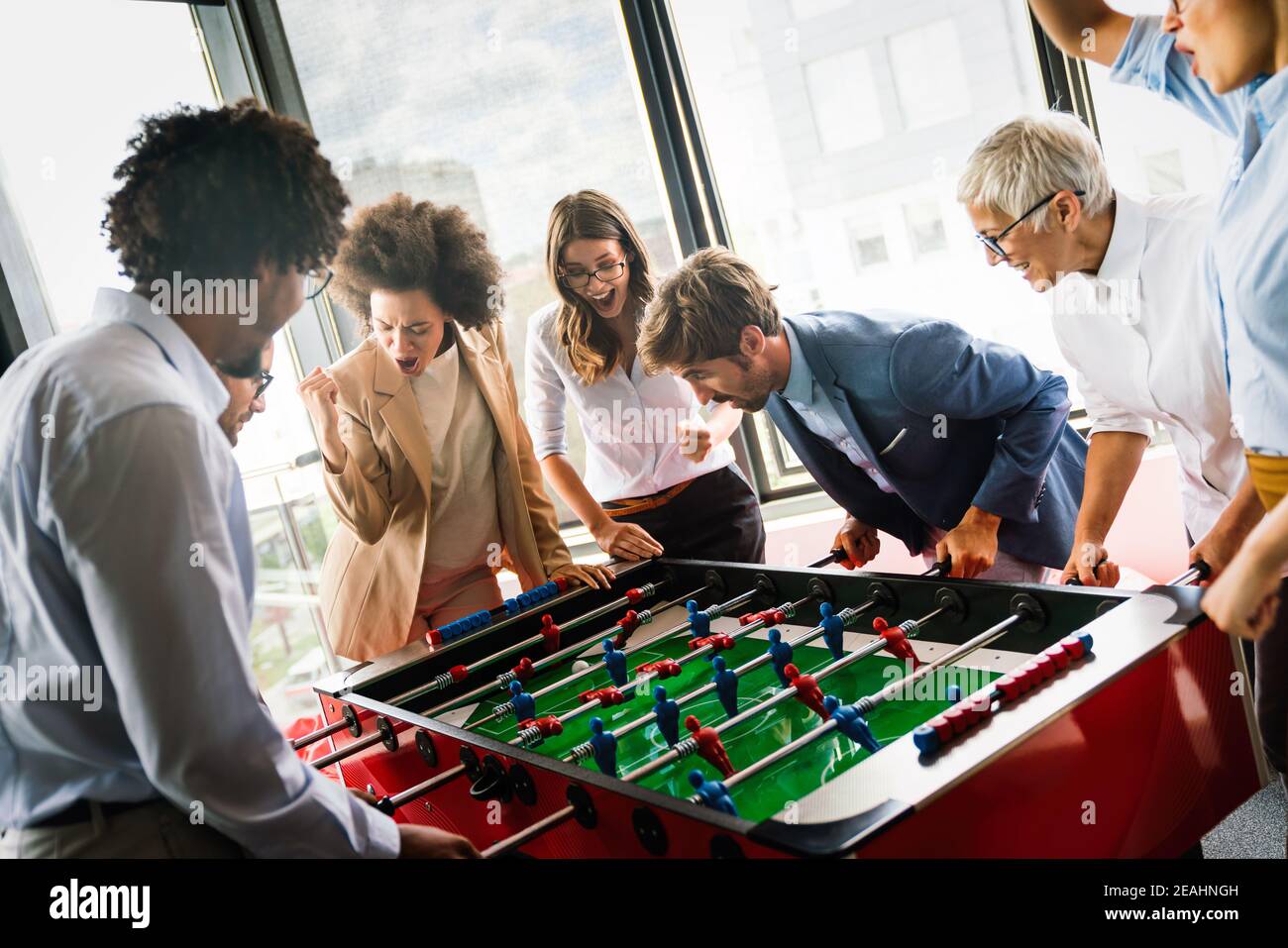 Employees playing table soccer indoor game in the office during break ...