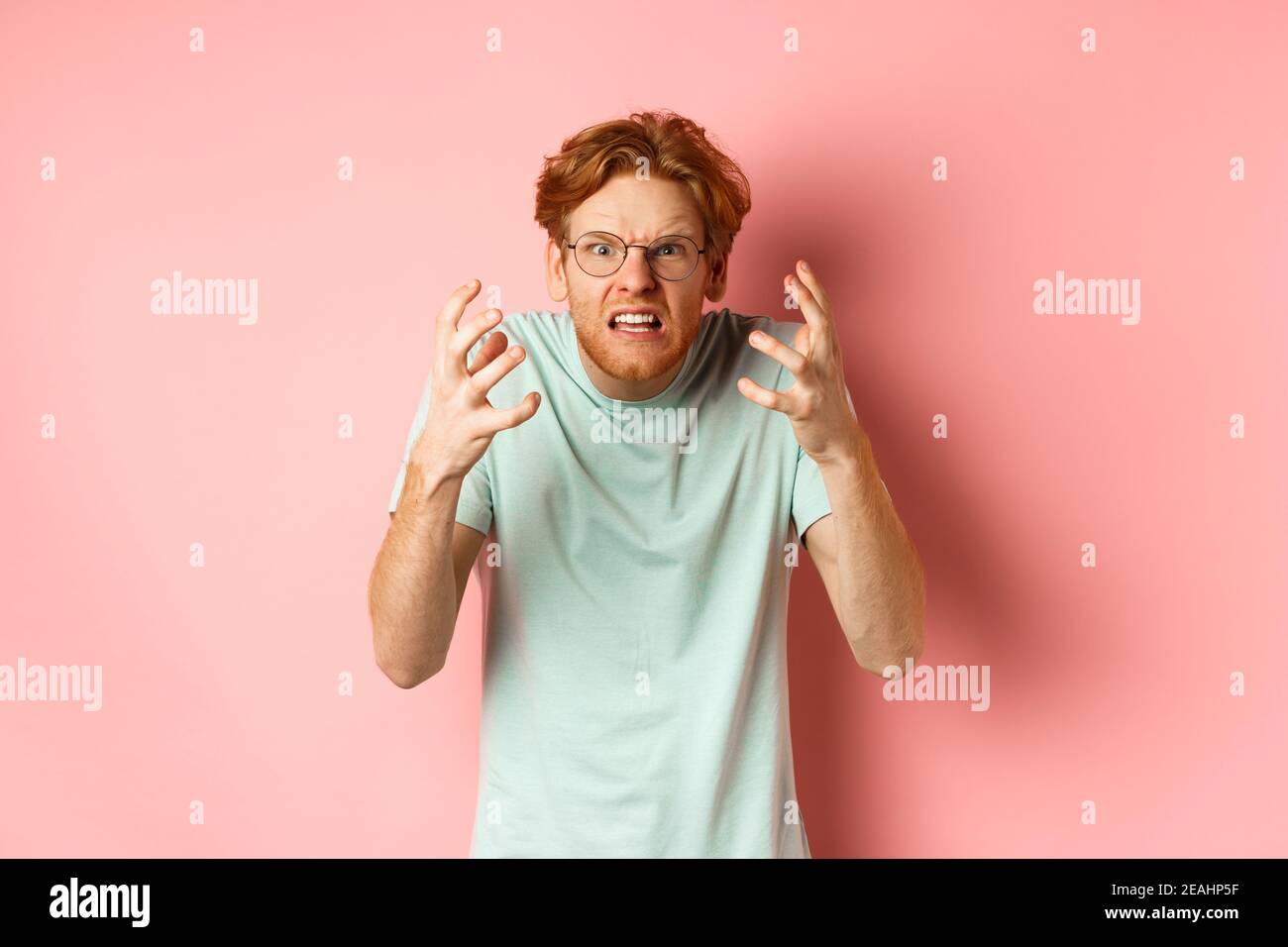Angry redhead guy in glasses shouting, frowning and shaking hands with ...