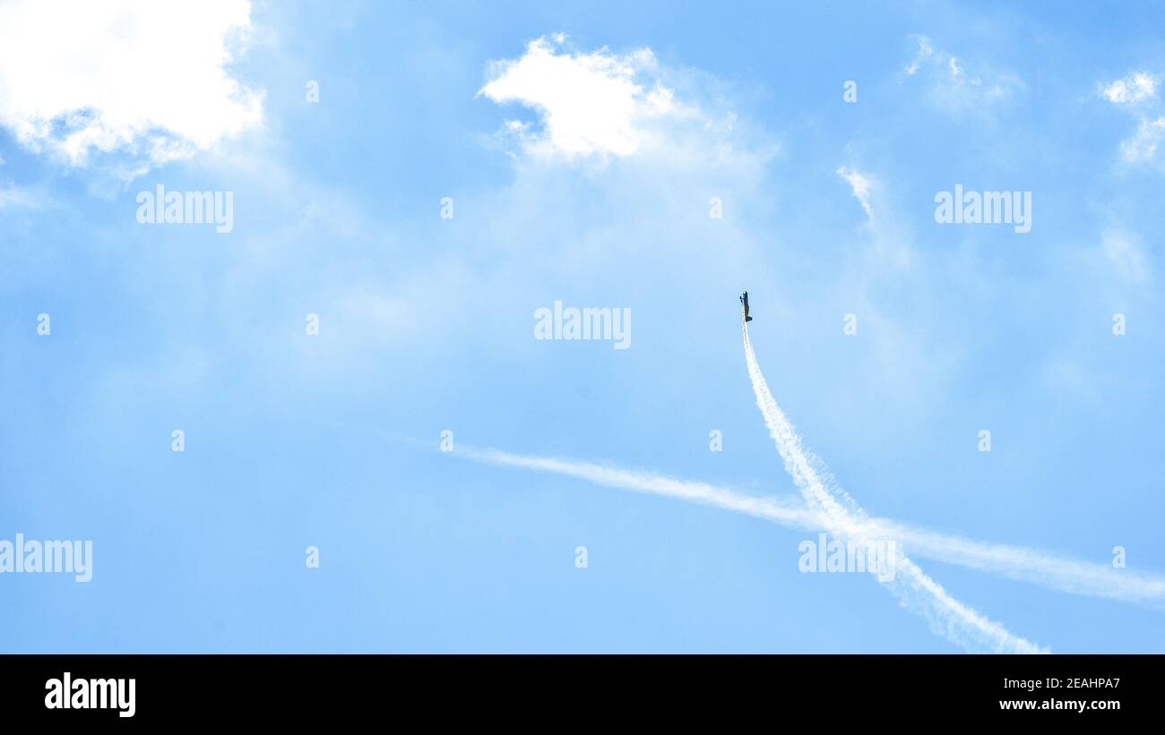 airplane doing acrobatics in blue sky leaves a smoke. Blue sky with ...