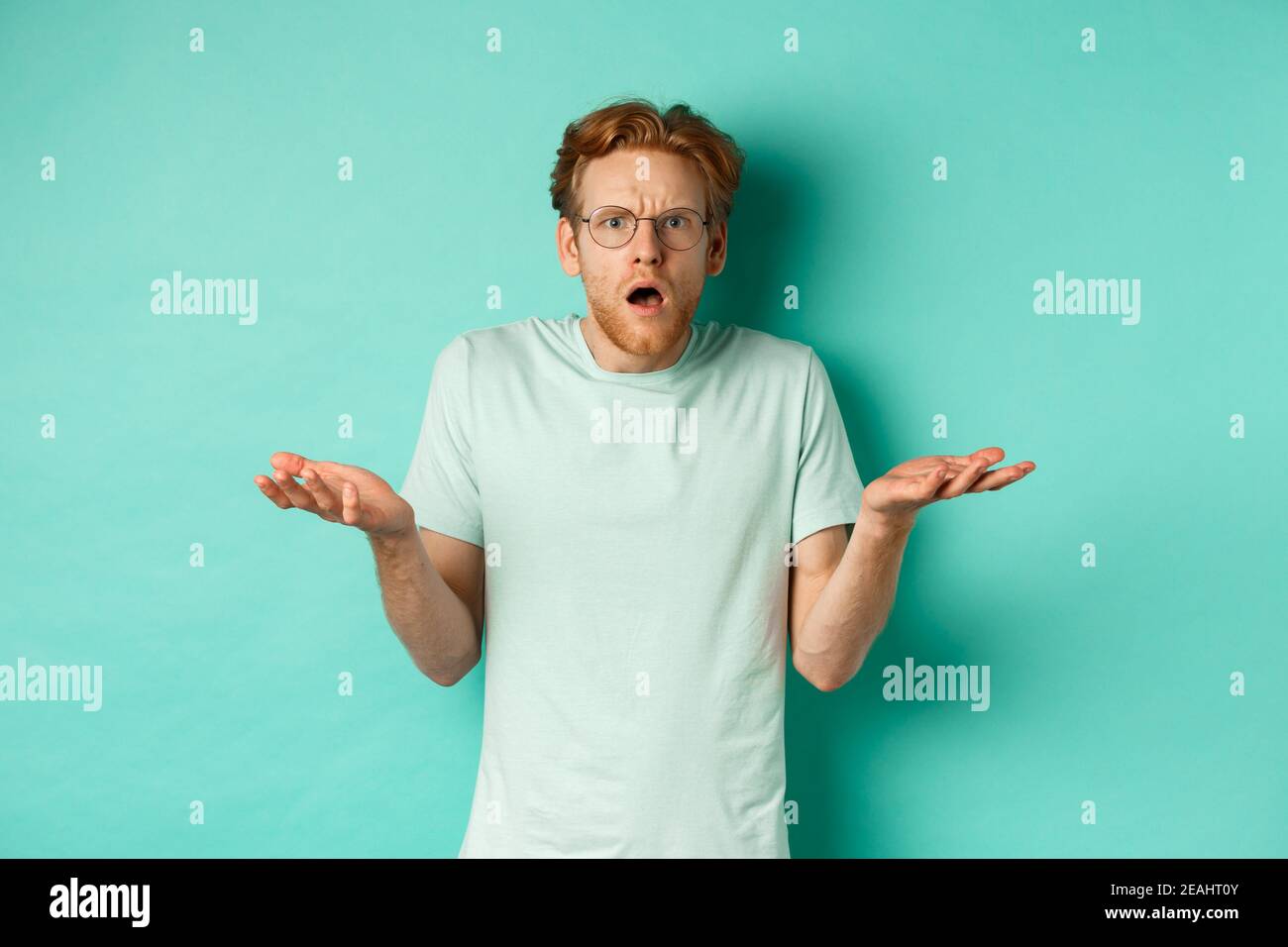 Confused and shocked guy with red messy hair and glasses, shrugging and ...