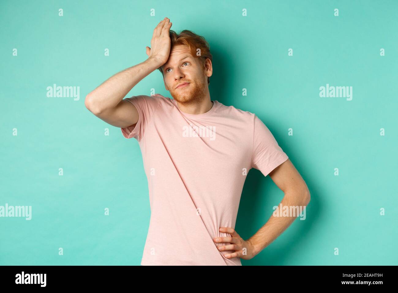 Annoyed and bothered redhead male model showing facepalm and roll eyes ...
