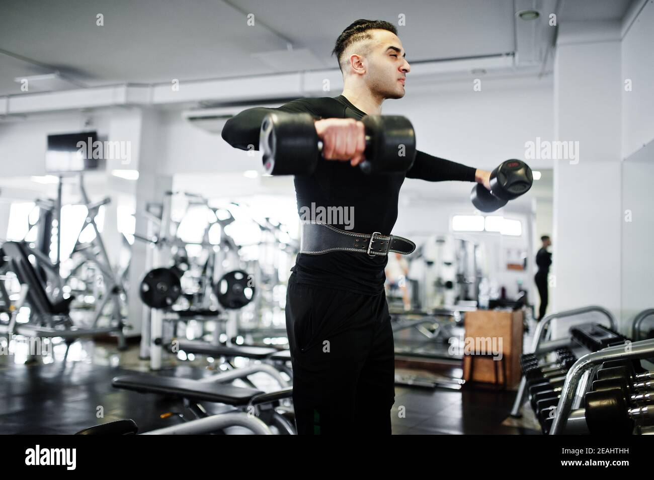 Muscular arab man training with dumbbells in modern gym Stock Photo - Alamy