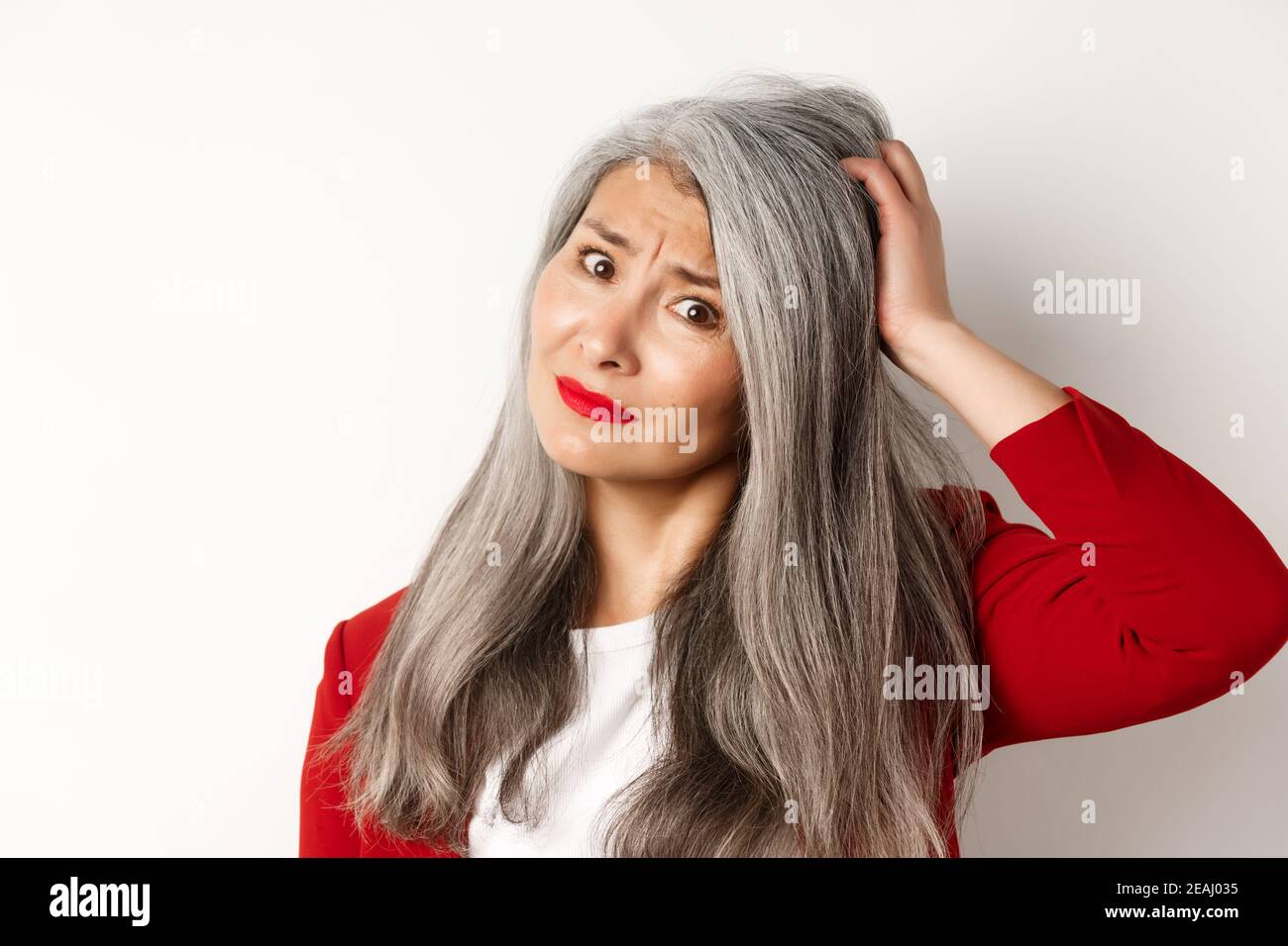 Close up portrait of confused asian female manager scratching head and ...