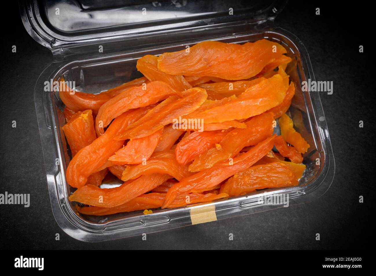 Dried mango on a in a plastic box on dark background. Selective focus ...