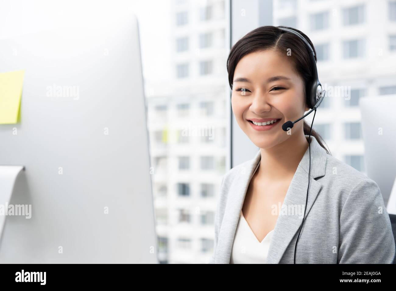 Smiling beautiful Asian woman working in call center city office as a customer service operator ...