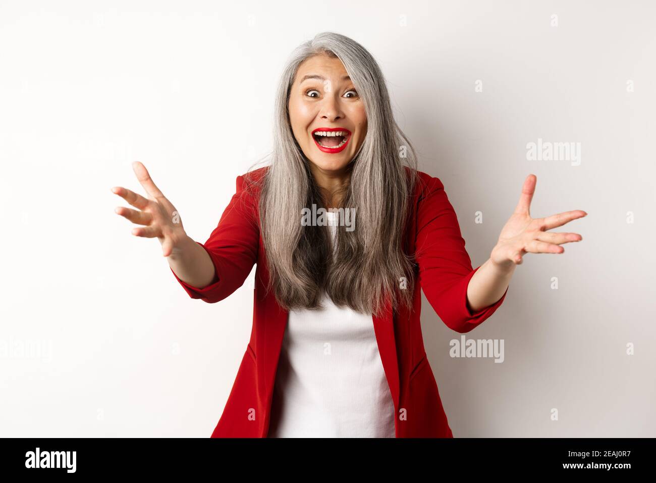 Surprised and friendly asian woman reaching hands forward and smiling ...
