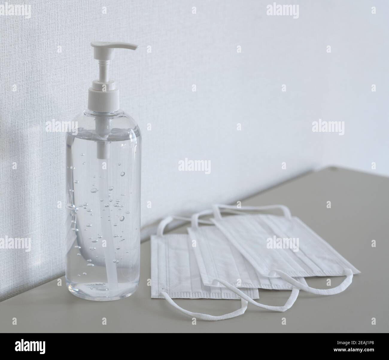Sanitizing gel and mask in front of the white wall Stock Photo - Alamy