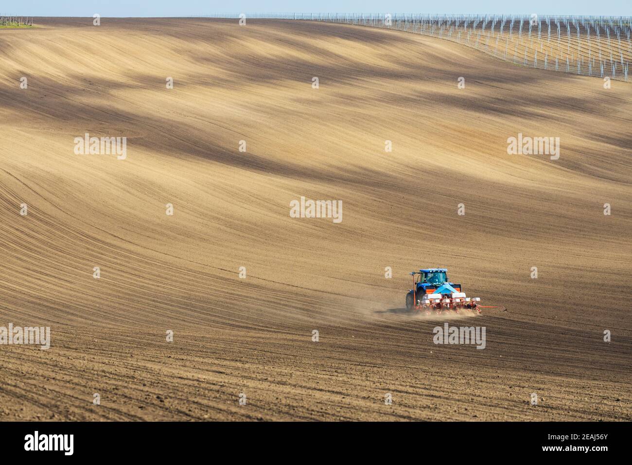Tractor with seed drill in early spring landscape Stock Photo - Alamy