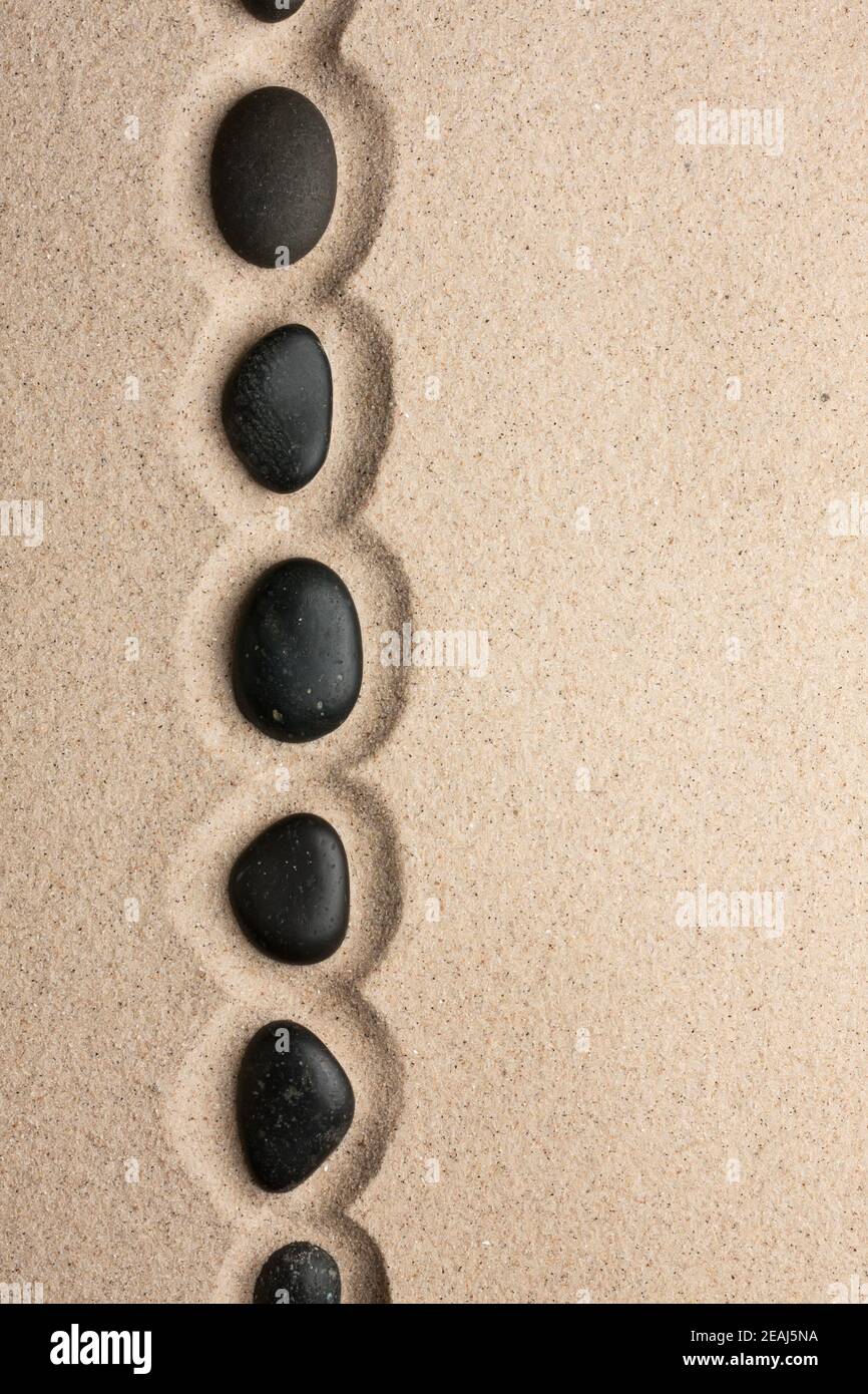 Line of black stones lying on the sand Stock Photo - Alamy