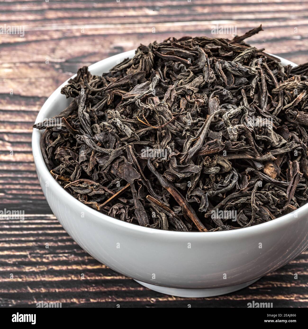 Dried tea is poured into a ceramic cup on a wooden plank table Stock ...