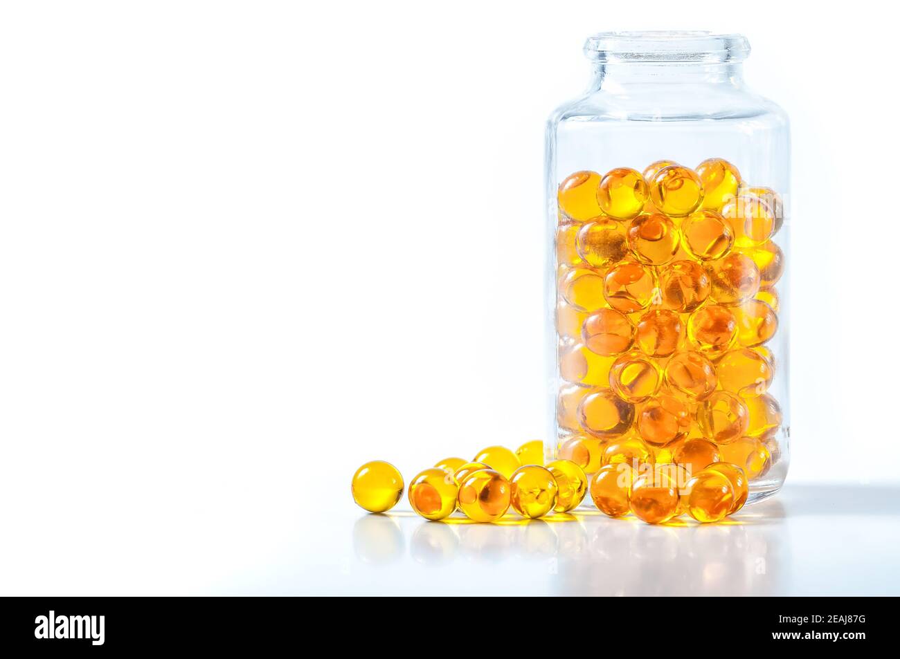Yellow capsules scattered from a glass jar on a white background Stock ...