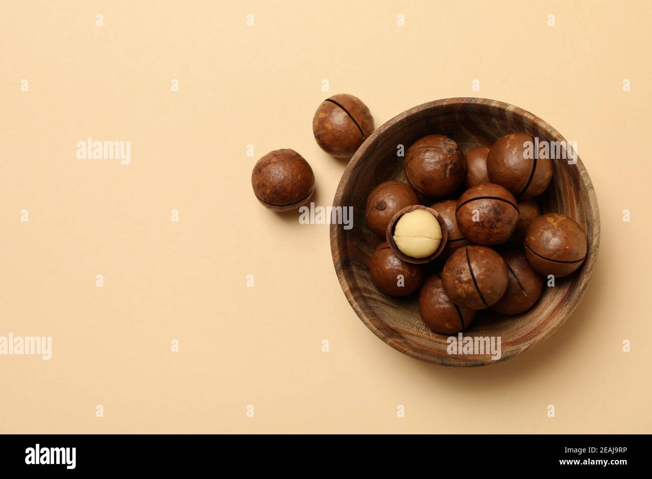 Bowl with tasty macadamia nuts on beige background Stock Photo - Alamy