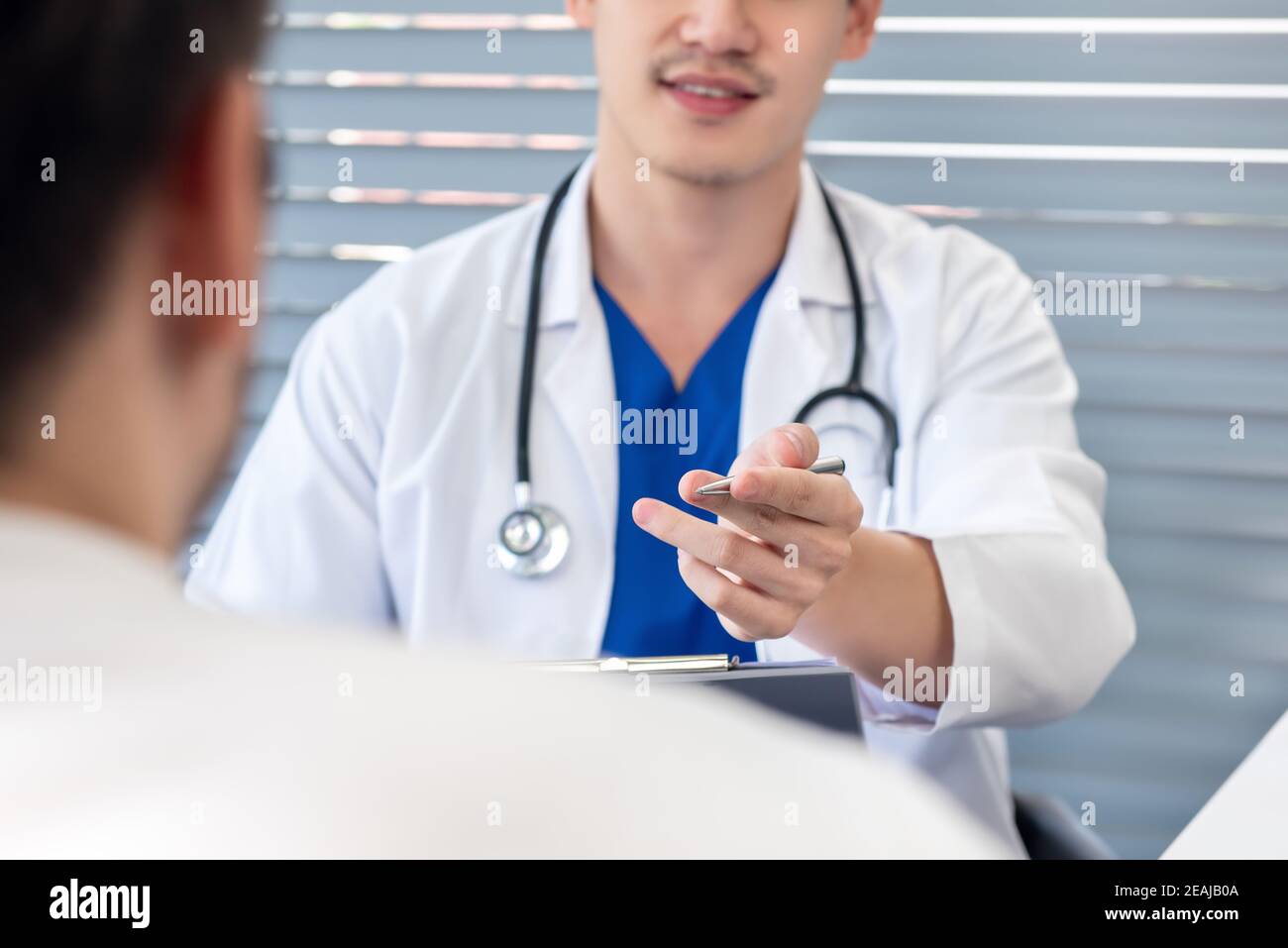 Doctor wearing coat and stethoscope around neck examining patient ...