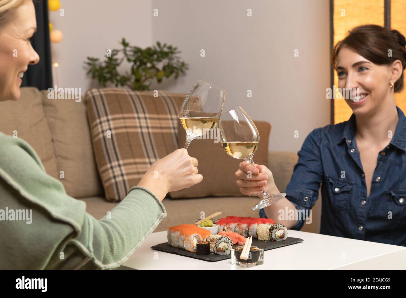 Two women friends sitting by table and eating sushi. Family, friendship ...