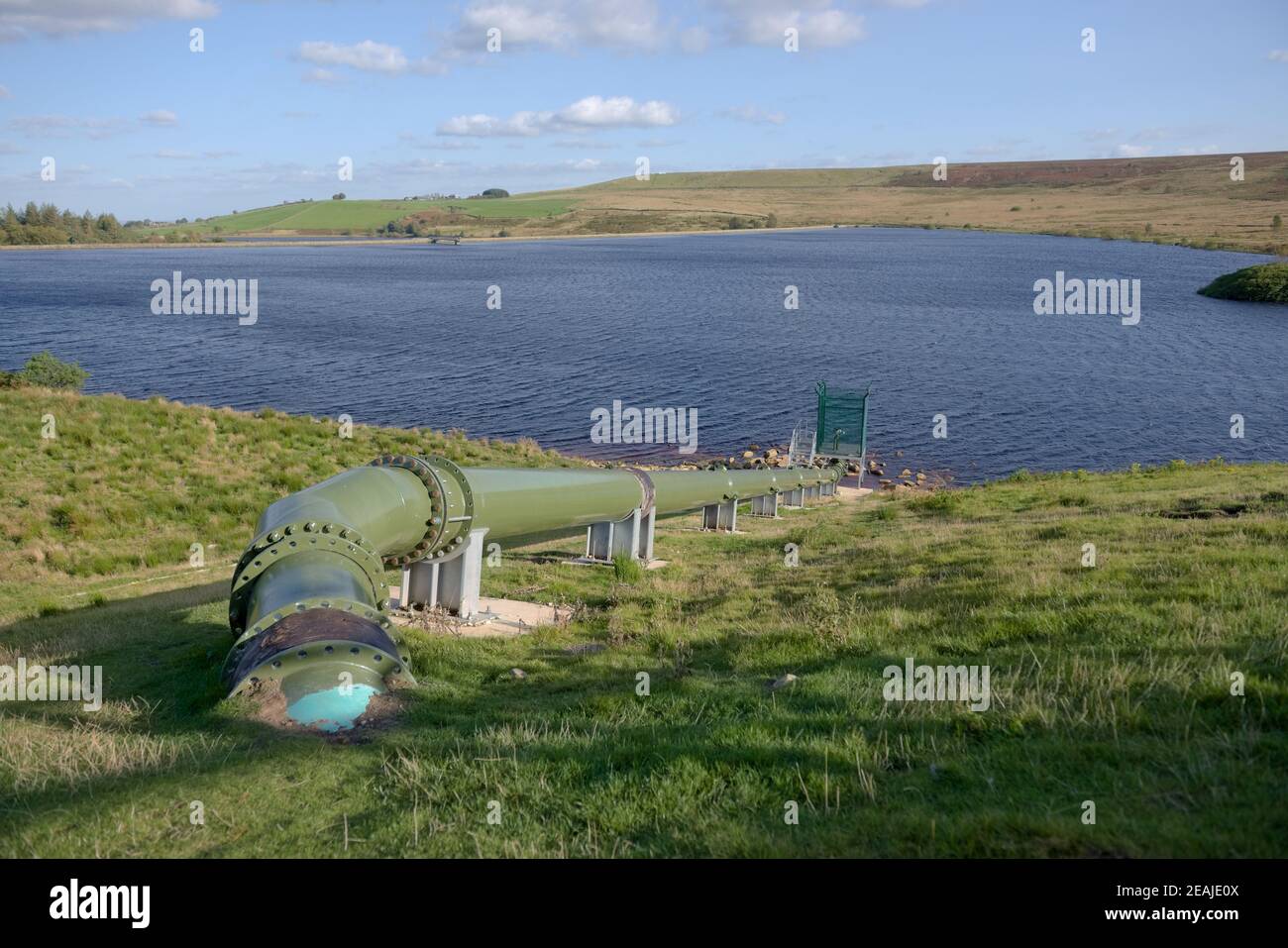 Very large shiny green metal pipe feeds into an extensive reservoir ...