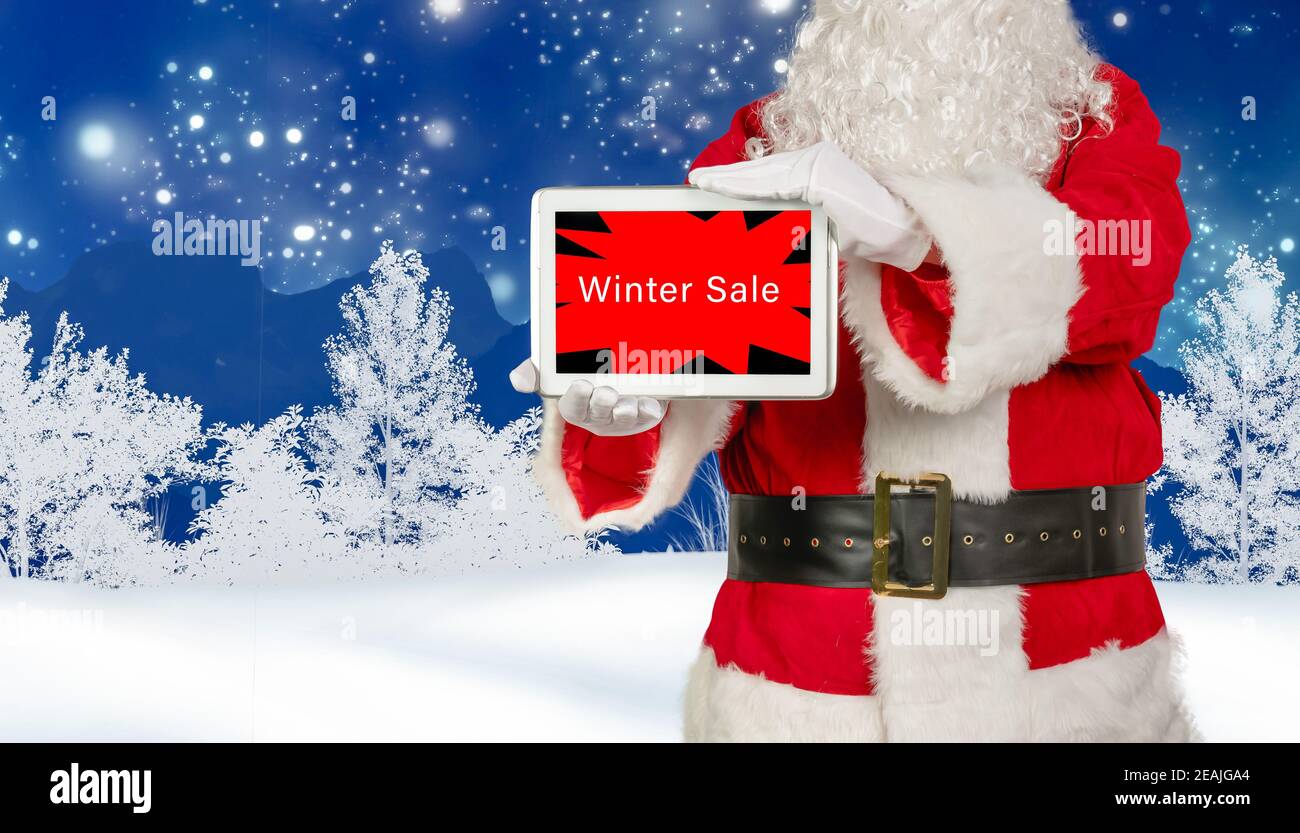 santa holds tablet with winter sale advertising on wintery background ...