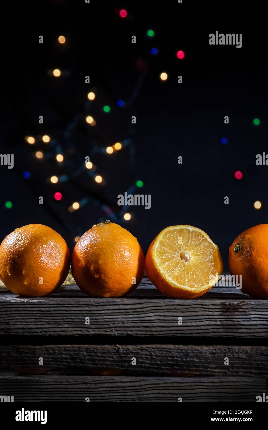 A row of orange clementines on a barn wood board with background lights ...