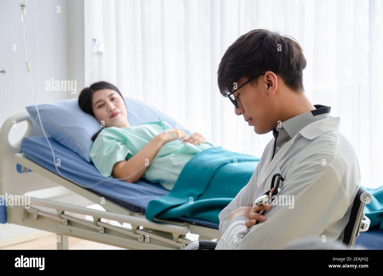 Tired Doctor in white uniform napping at hospital ward for caring ...