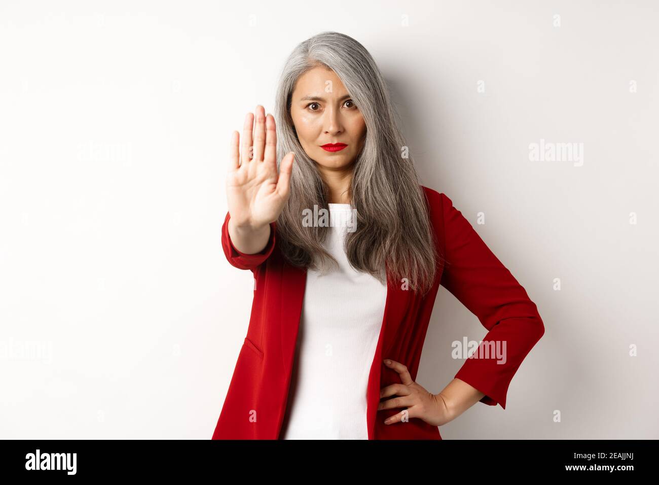Serious asian woman in red blazer showing stop sign, telling no ...