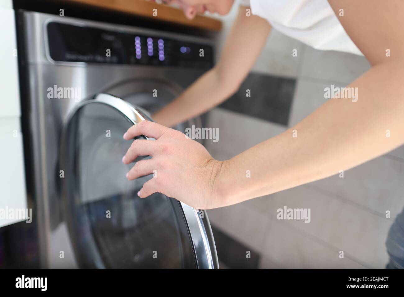 Woman opens door of washing machine closeup Stock Photo - Alamy