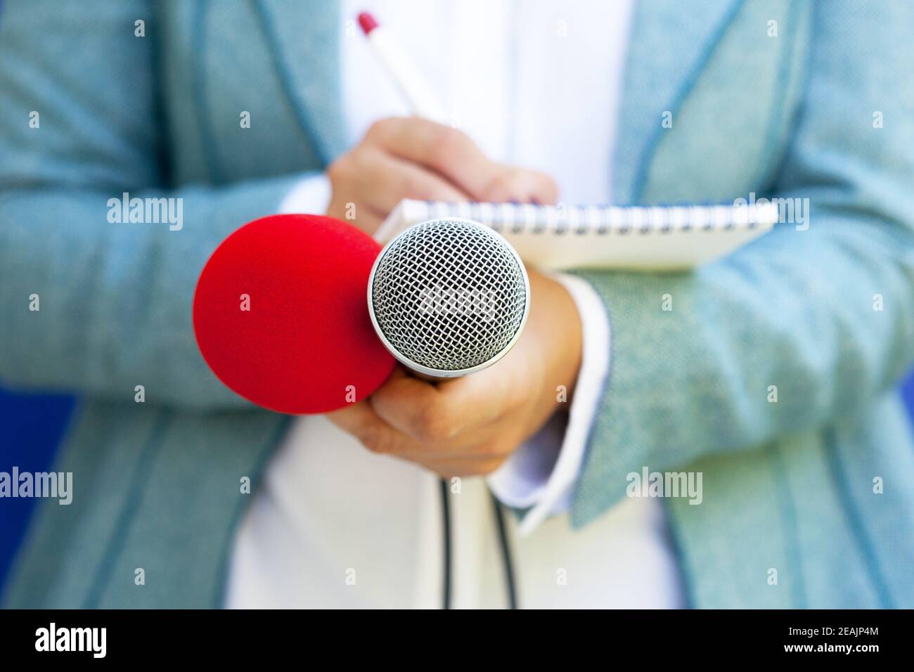 Female reporter at press conference, writing notes, holding microphone ...