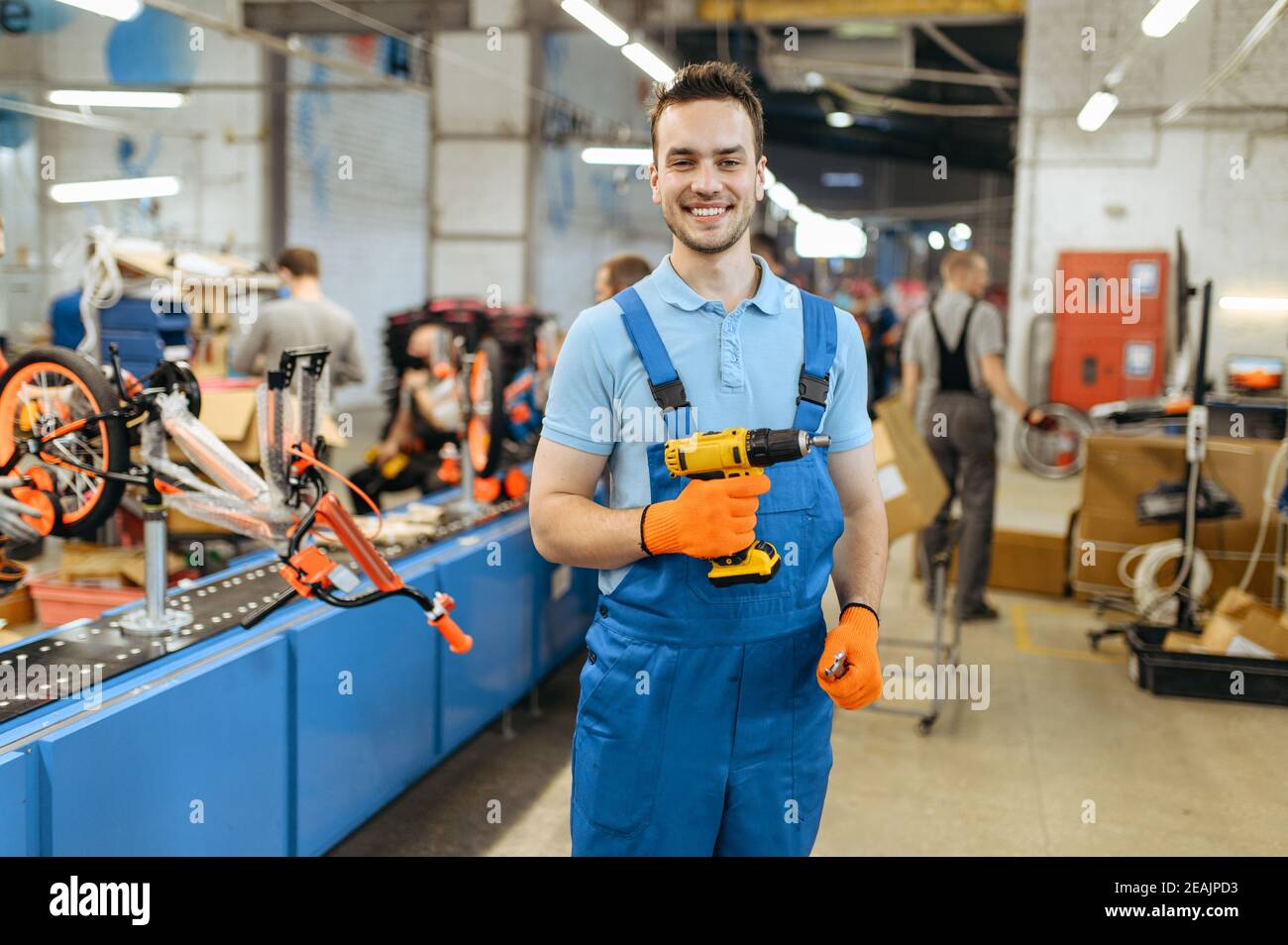 Bicycle factory, worker holds electric screwdriver Stock Photo - Alamy