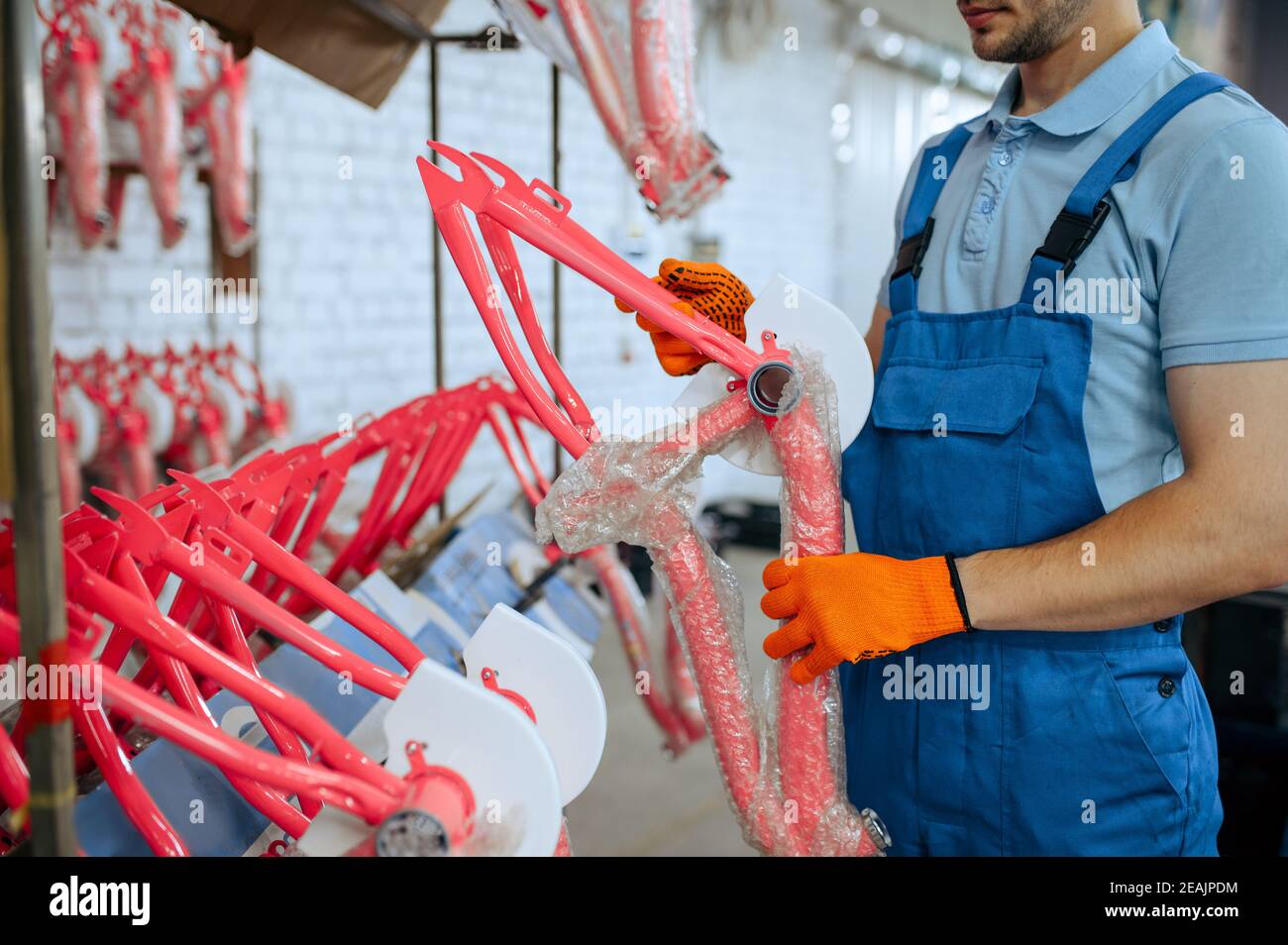 Bicycle factory, worker holds kid's bike frame Stock Photo - Alamy