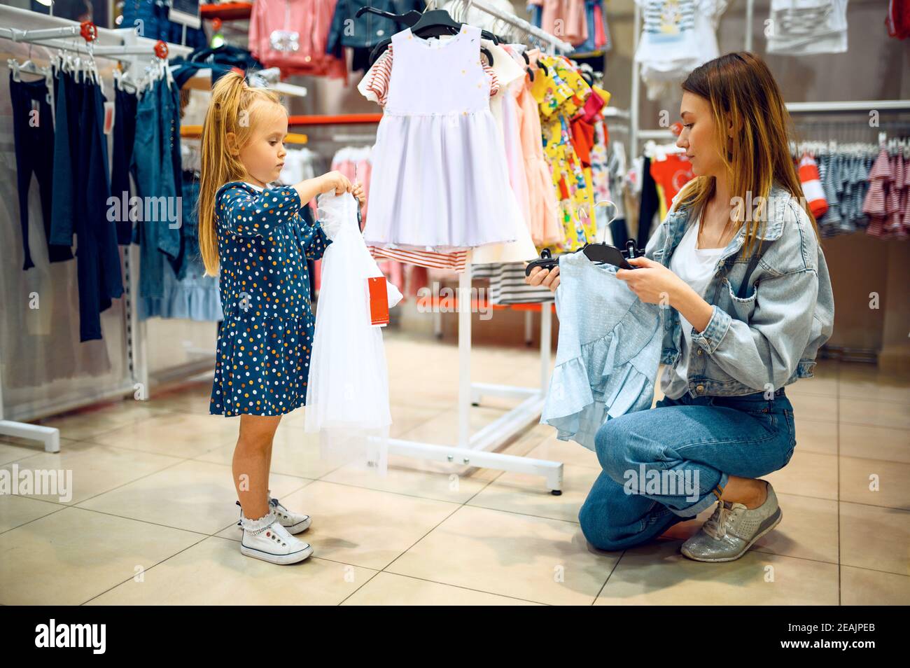 Mother and little baby buying dress in kid's store Stock Photo - Alamy