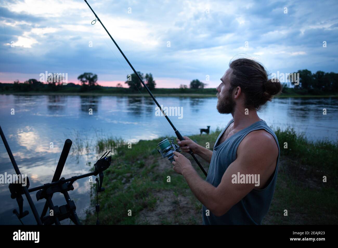 Angler on a river bank at twilight Stock Photo - Alamy