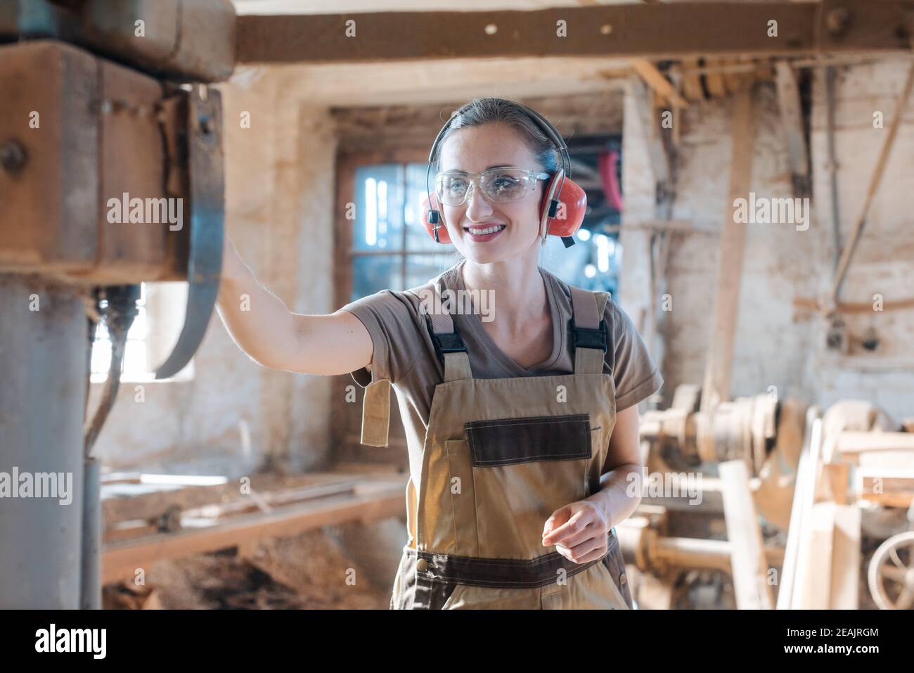 Woman carpenter in traditional carpentry adjusting the machine planer ...