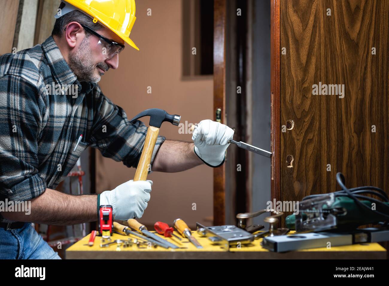 Carpenter at work repairs and installs the door lock. Carpentry Stock ...